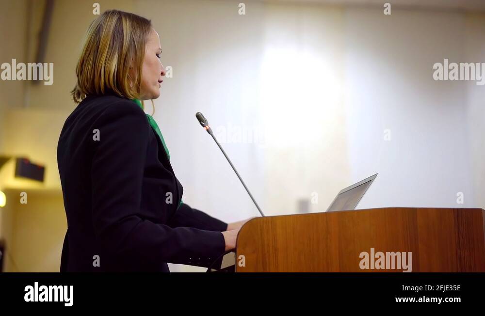 woman politician is speaking in large auditorium, reading her ...
