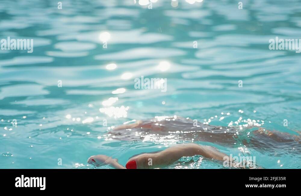 Two woman`s hands with water drops rise over swimming pool with a sun ...