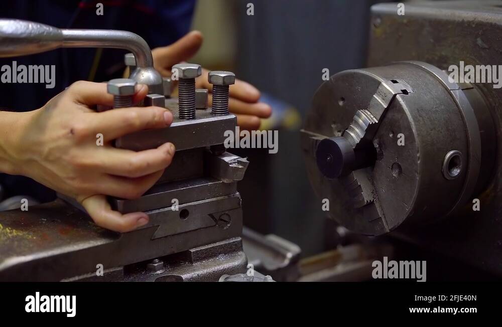 worker of plant is adjusting a rotary machine, turning handles and ...