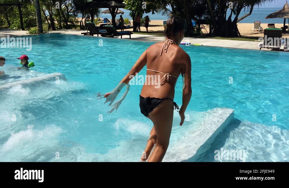 Tracking shot of a teenage girl diving into a swimming pool at a tropical Stock Video Footage ...