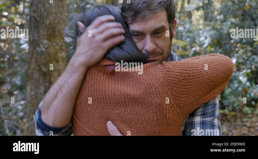 Sad, upset young man hugging a woman who is comforting him while ...
