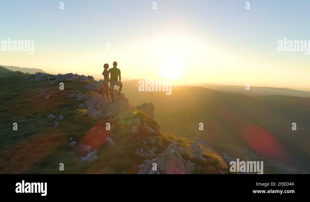 LENS FLARE: Flying near male and female hikers watching the beautiful ...