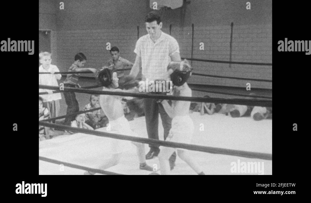 1950s: Gym. Man referees boxing match. Boys punch each other Stock ...