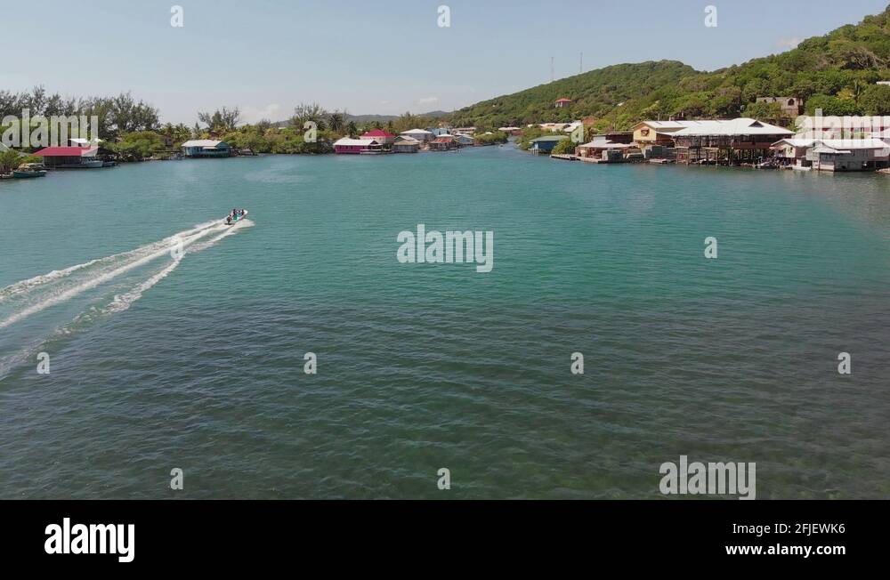 Low flight over Caribbean fishing village waterway inlet and overtaking ...