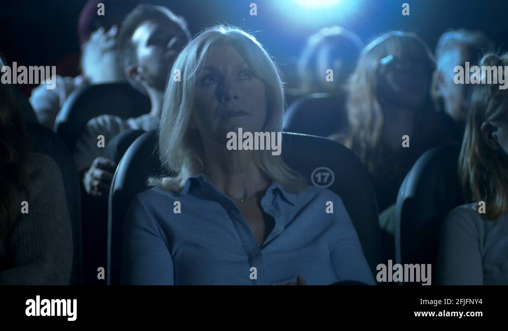 Frightened woman at the cinema jumps at a scary moment in the film ...