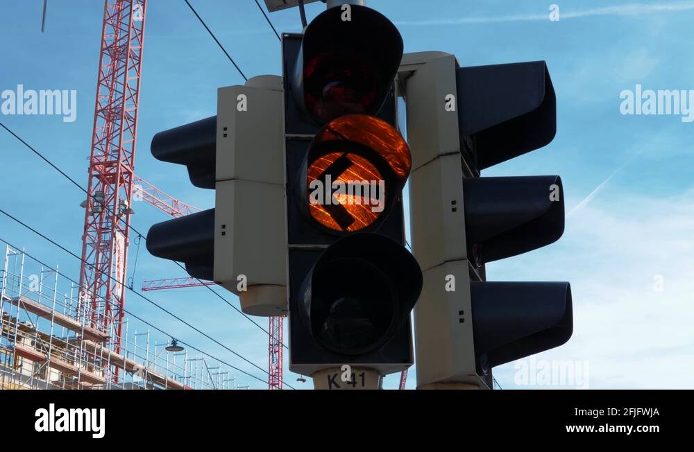 Traffic light flashes at building site. A red crane is in the ...
