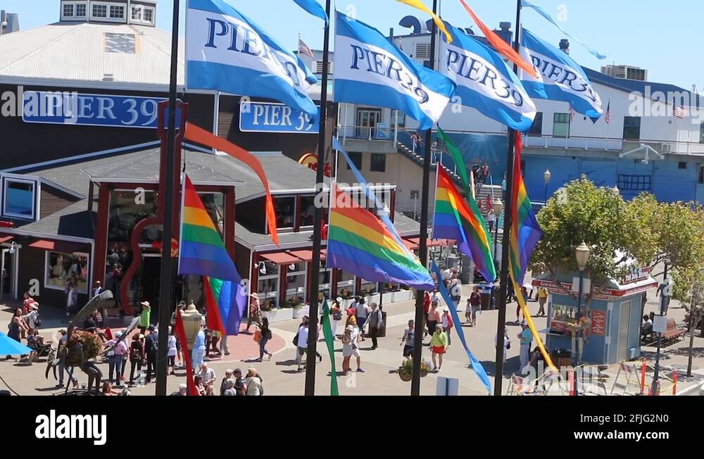 Gay pride flags on display at Pier 39 flag poles as tourists walk in the Stock Video Footage - Alamy