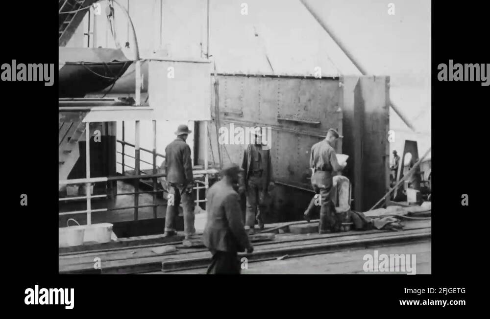 Crane lower supplies on the dock and workers load boxes on the puller ...