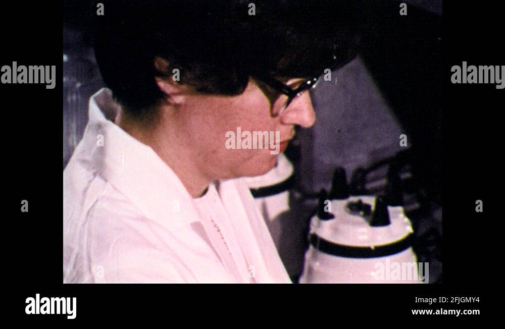 1960s: Chemistry lab, woman in white coat at bench full of glassware ...