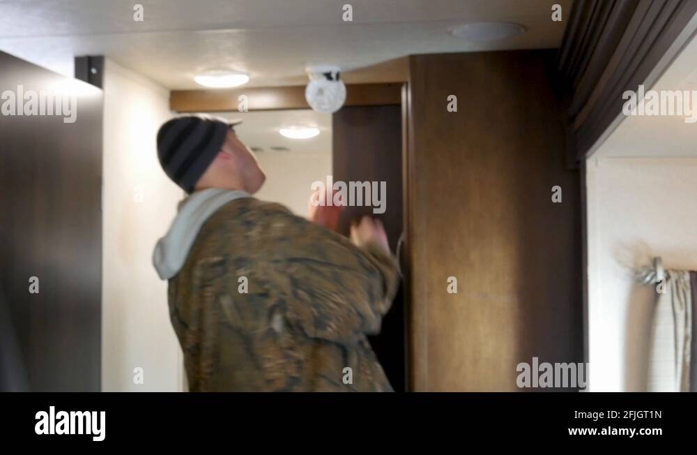 2 men changing the batteries in a smoke detector. The smoke detector is ...