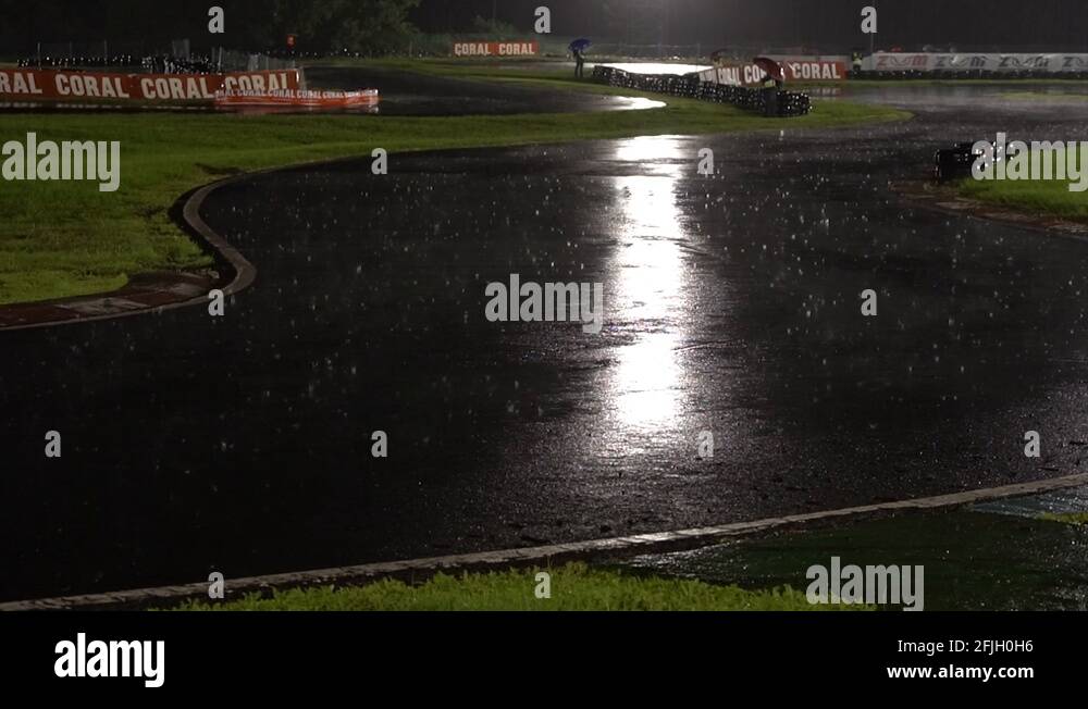 A race car track all wet with rain at night with light reflection on ...