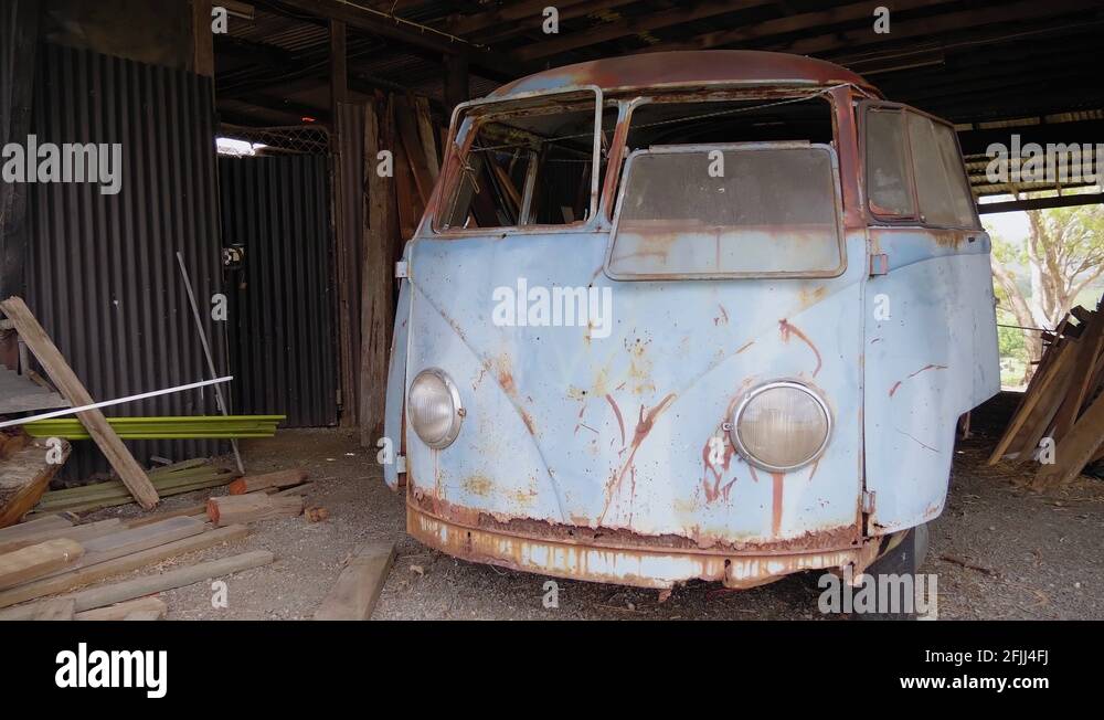 A panning sliding shot of a 1960's split screen blue VW kombi bus with ...