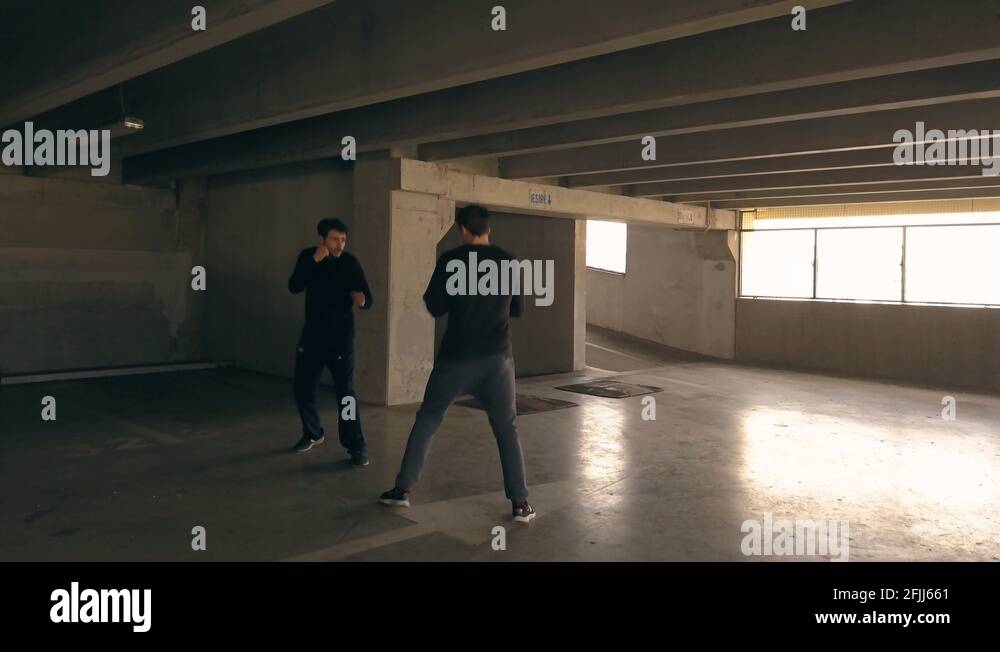 Two male actors rehearse a fight scene in a parking deck. Sunlight ...