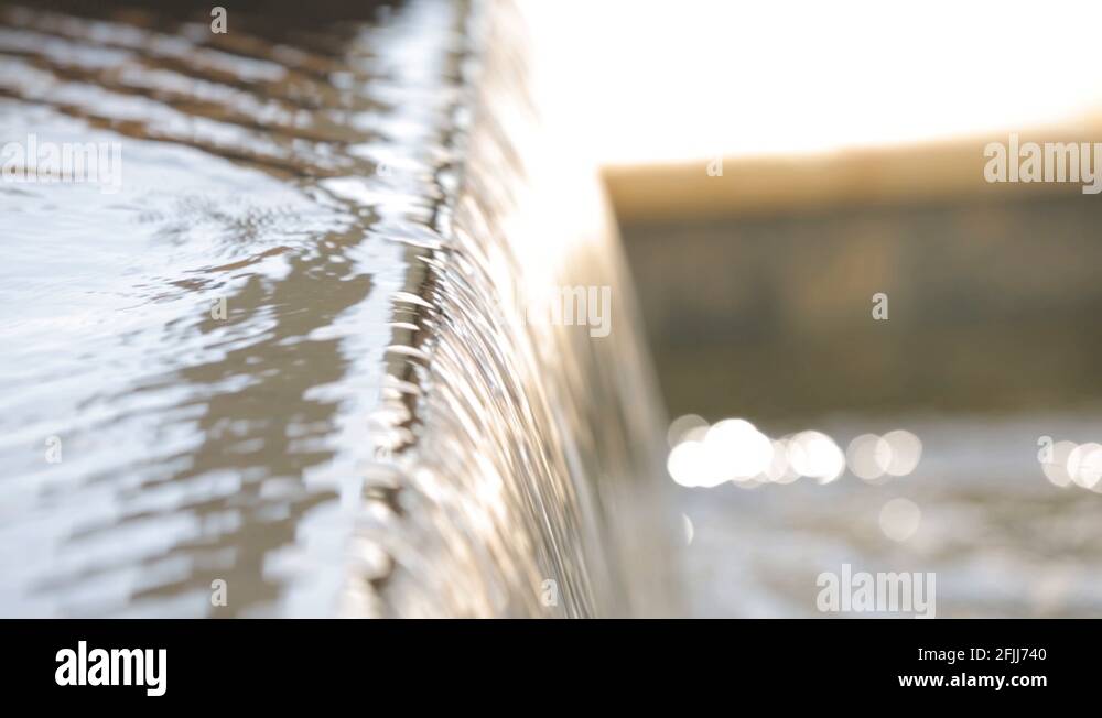 Close up static shot of water as it flows over a spillway in a pool ...