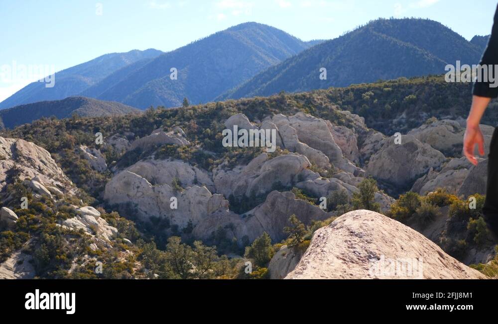 A handsome young man on a hike walking to the edge of an awe inspiring ...