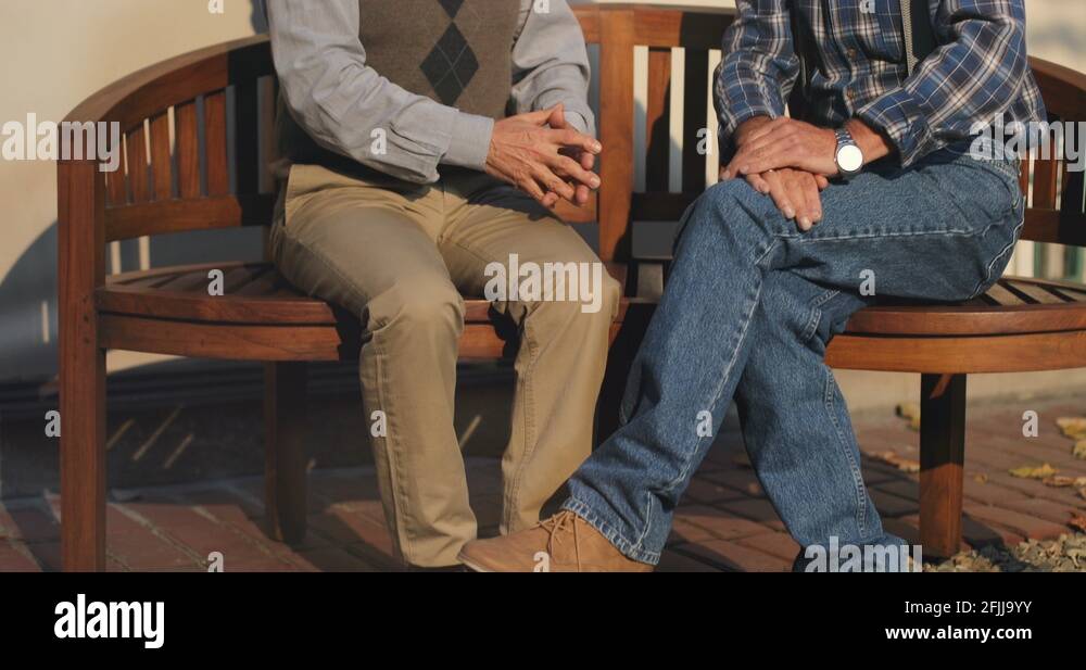 Two old Caucasian male friends on retirement sitting on the bench ...