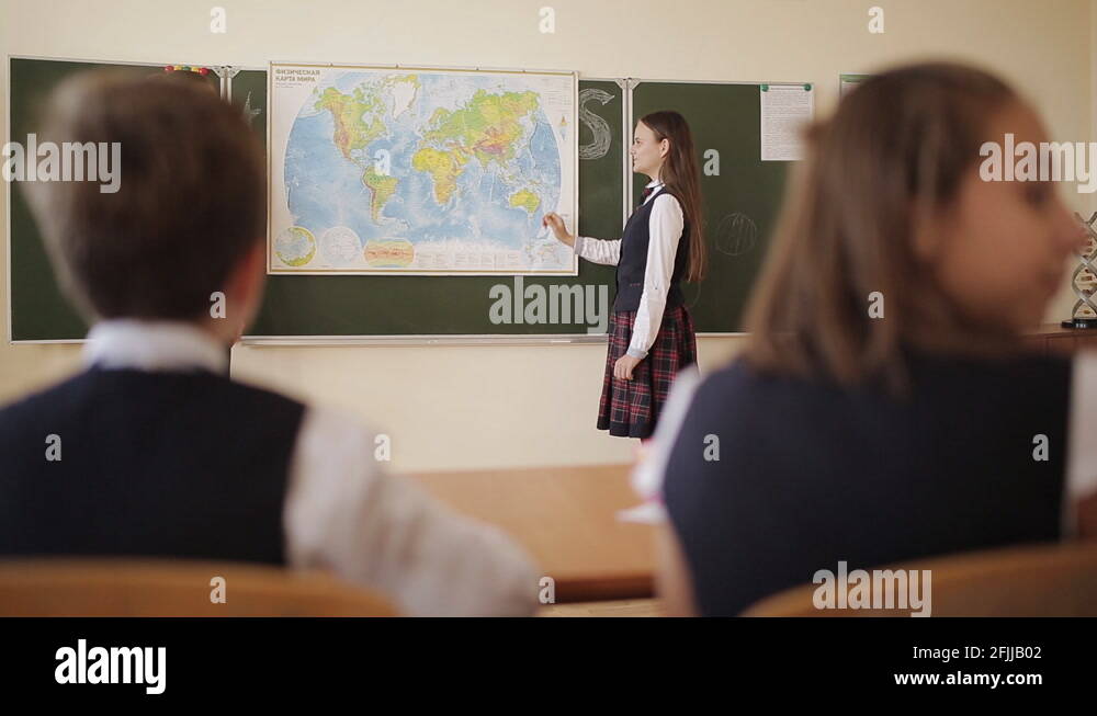 Geography lesson. Pupil in school uniform on the world map answers the ...