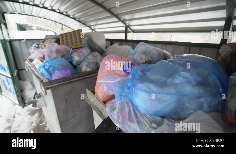 Garbage bins filled with trash man throwing garbage bag into waste ...