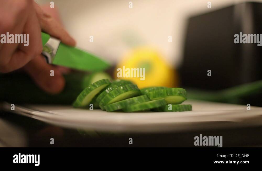 Cutting up Cucumber at home on White chopping board, with green knife ...