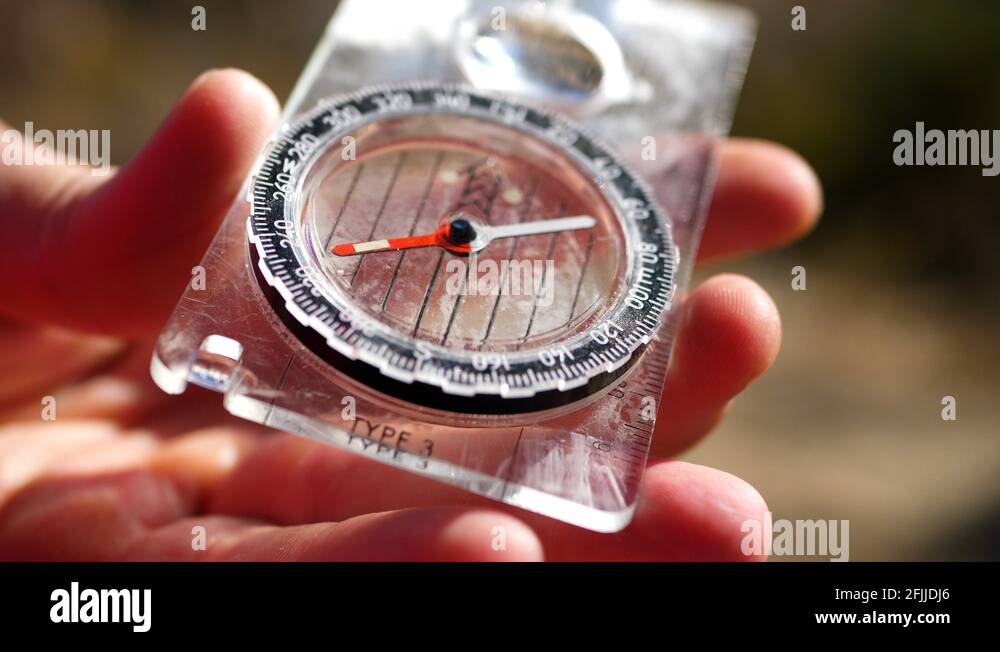 Close up on the needle spinning of a magnetic compass finding north on ...