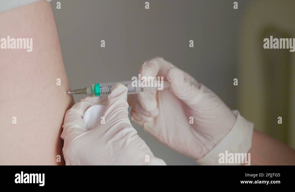 Close-up of the hand of a medic administering an intramuscular ...