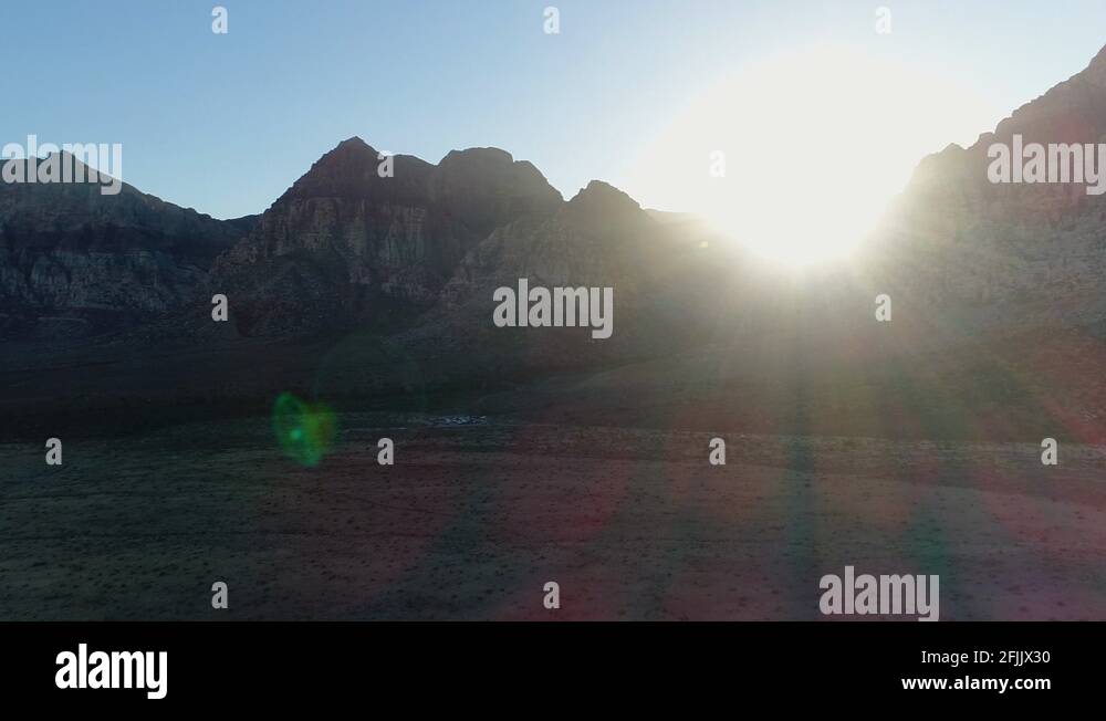 A ray of light beaming through a gap between monumental mountains in a ...
