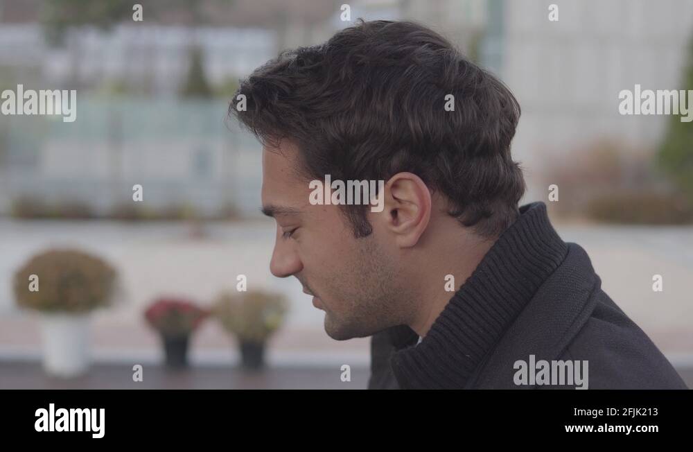 Pan down on businessman sitting outdoors and working on laptop closeup ...