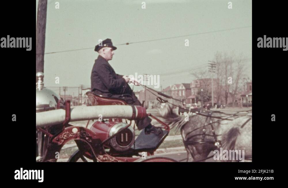 1920s: Parade route turns corner, horse drawn fire engine, fireman ...