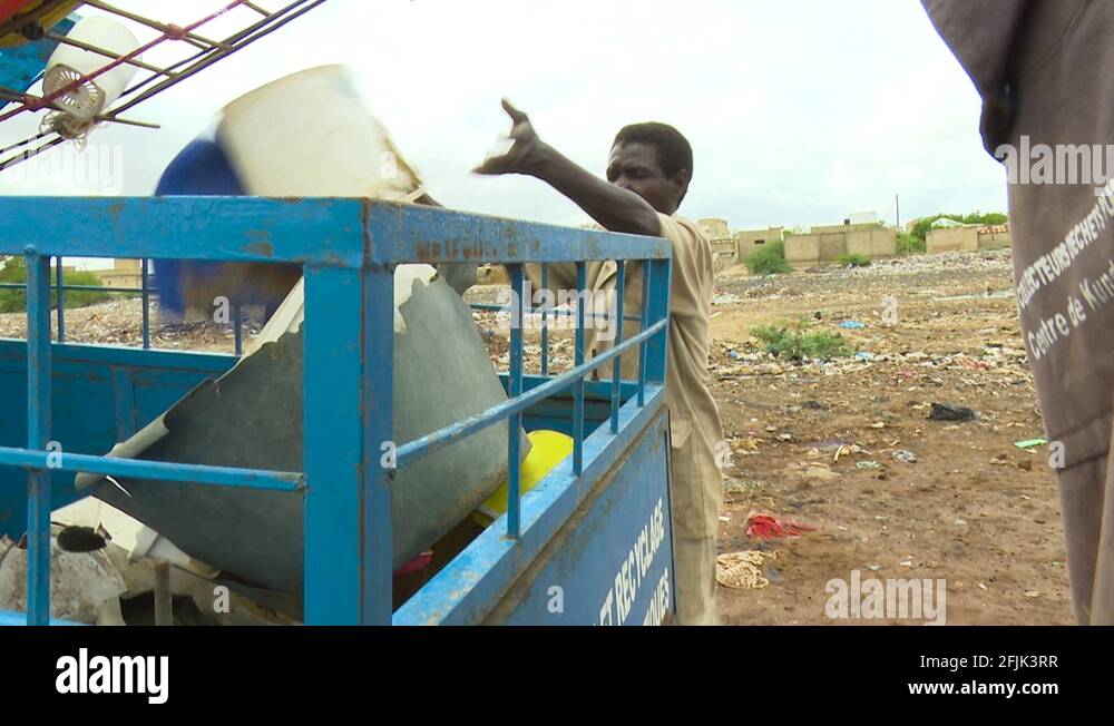 Two men loading a cart with plastic waste to take them to a recycling ...