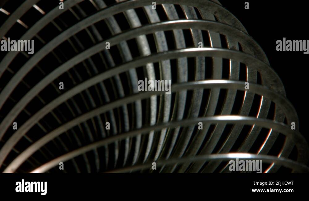 Toy metal spring. Isolated on black background. Zoom out camera reveal ...