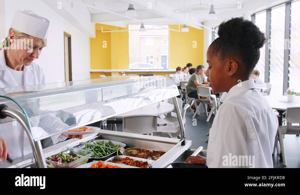 Female High School Student Wearing Uniform Being Served Food In Canteen ...