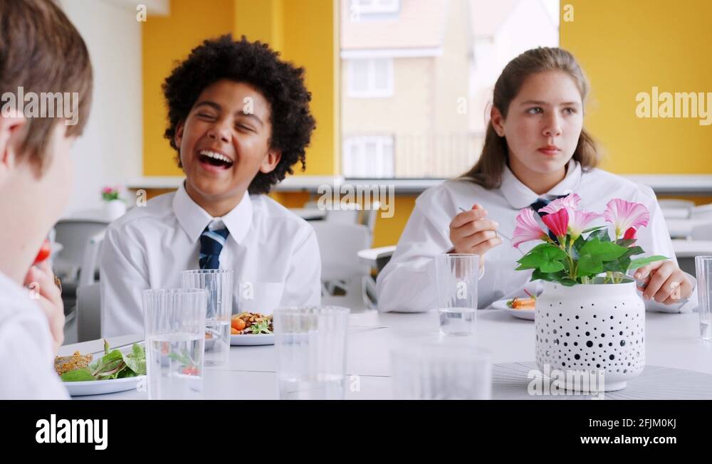 Group Of High School Students Wearing Uniform Sitting Around Table And ...