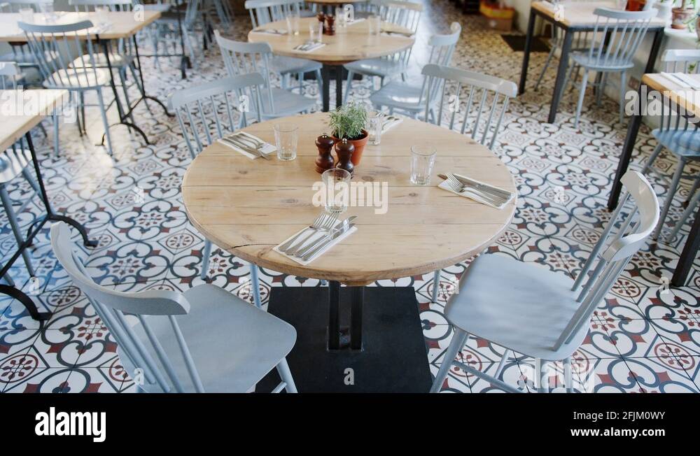 Empty place settings at a restaurant with round tables and duck-egg ...