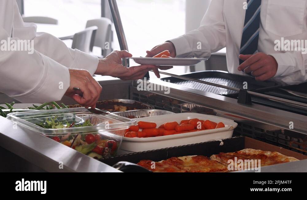 Close Up Of High School Students Wearing Uniform Being Served Food In ...