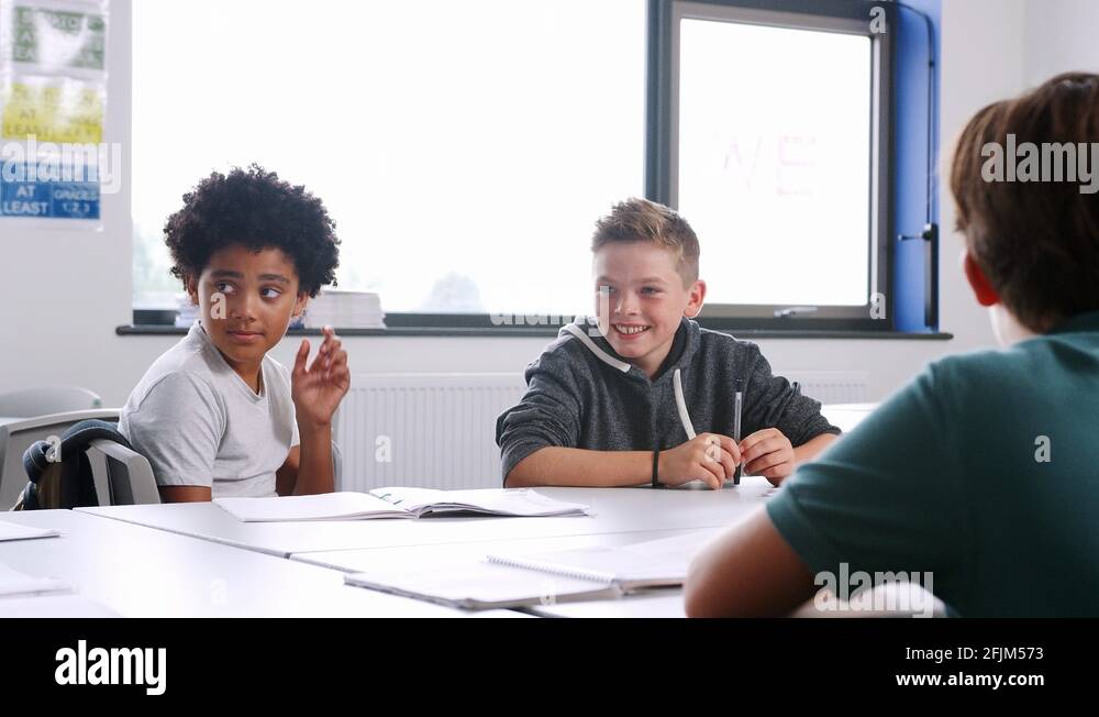 Three Male High School Students Sitting Around Table In Classroom ...