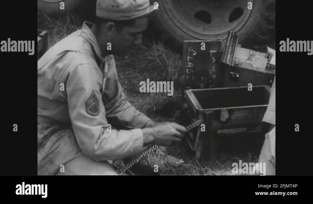Soldiers load ammunition strips on machine gun and fire - 1943 Stock ...
