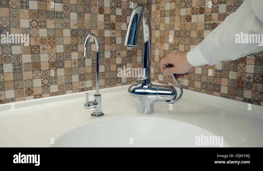 Hand opens ( closing ) the water tap and water flow into the washbasin ...