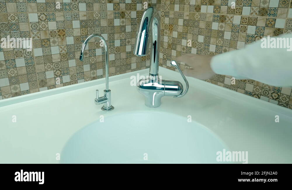 Hand opens ( closing ) the water tap and water flow into the washbasin ...