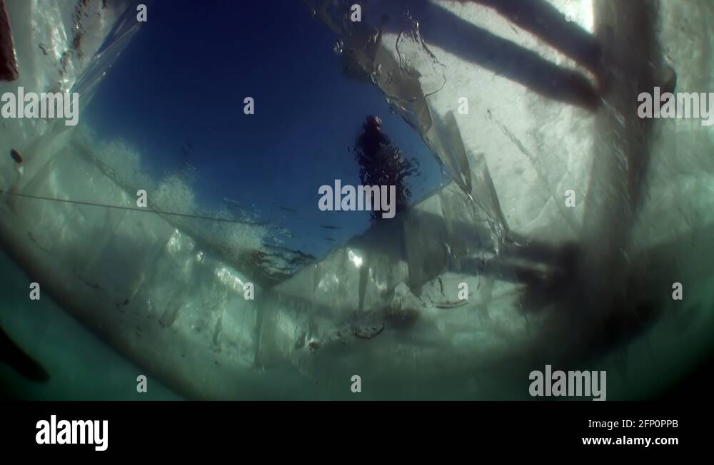 Underwater video shooting under ice of people near ice-hole on surface ...