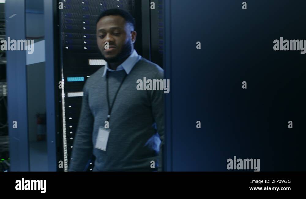 Black Handsome Employee Walks Through Server Corridor in a Data Center ...