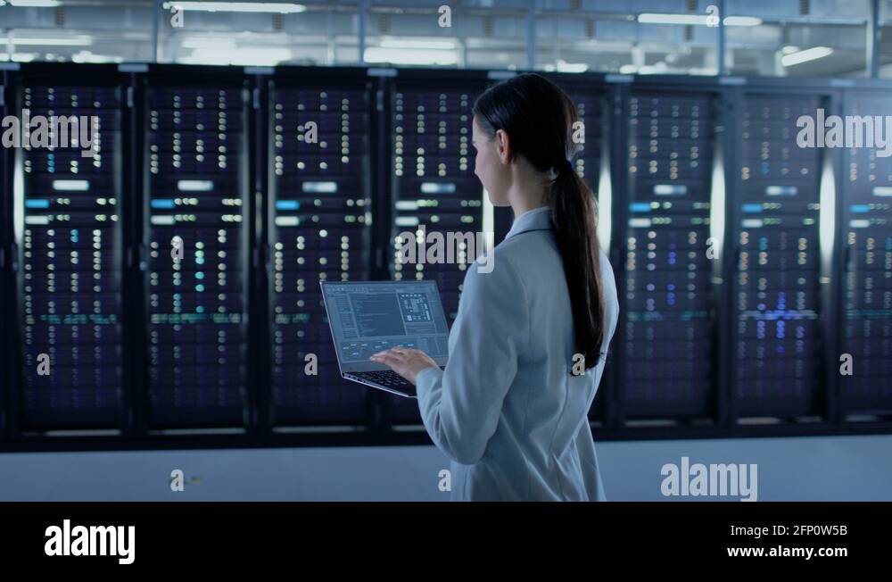 Female Data Center IT Specialist Works on Laptop Computer Next to ...