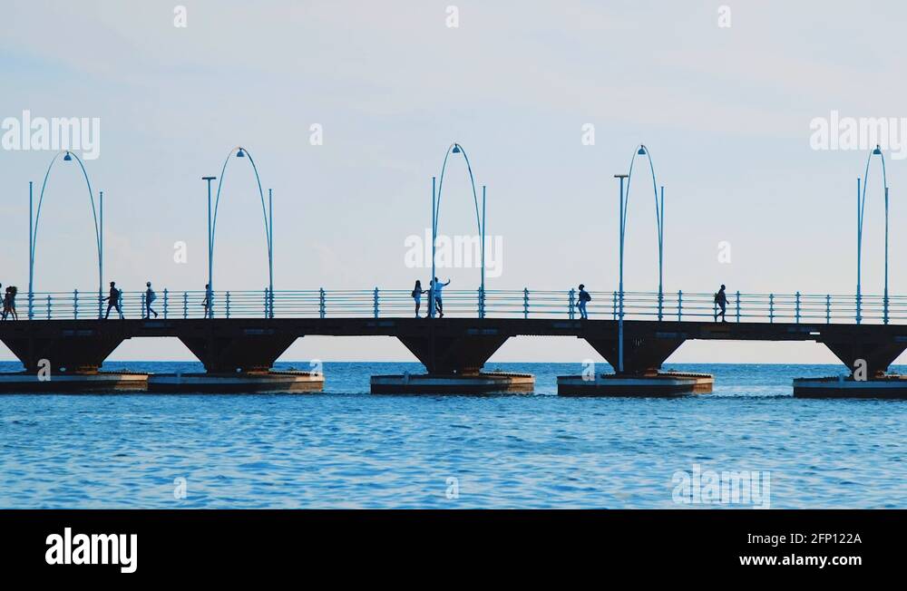 People walking across Queen Emma floating bridge in Willemstad, Curacao ...