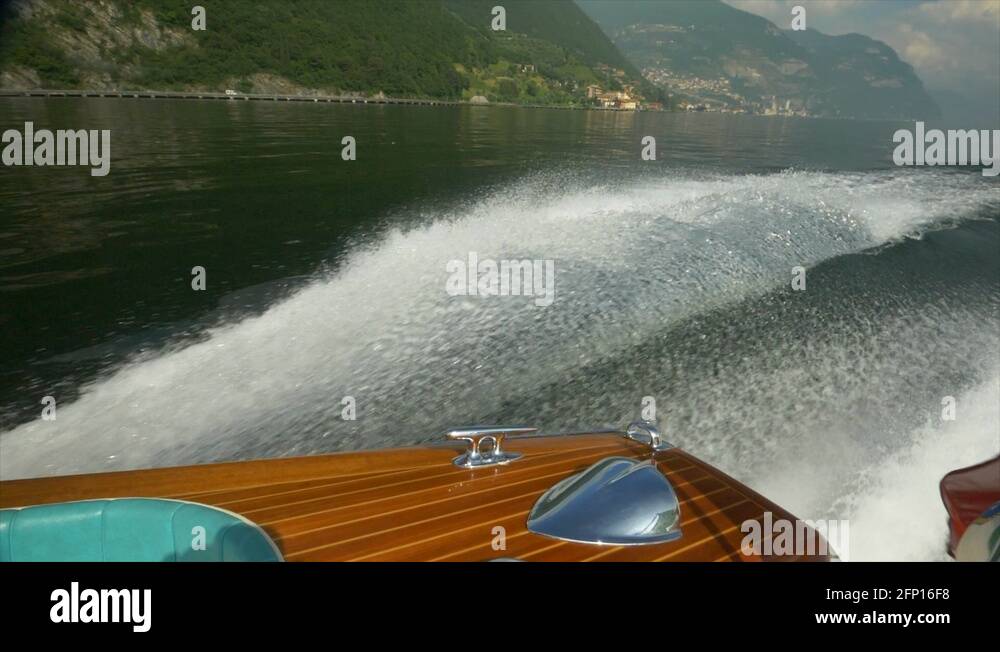 A classic luxury wooden runabout boat with an Italian flag on a lake ...