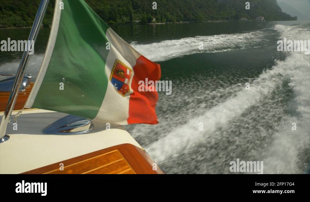 A classic luxury wooden runabout boat with an Italian flag on a lake ...