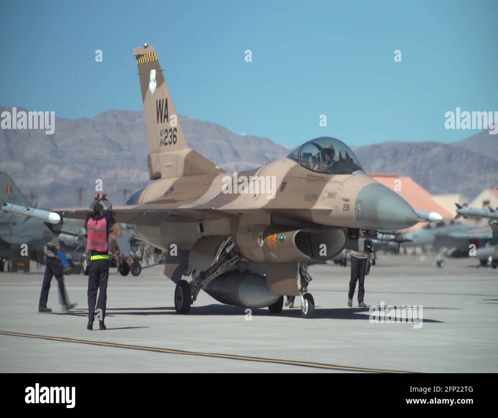 Crew placing wheel chocks at landing gear of F-16 Aggressor during Red ...