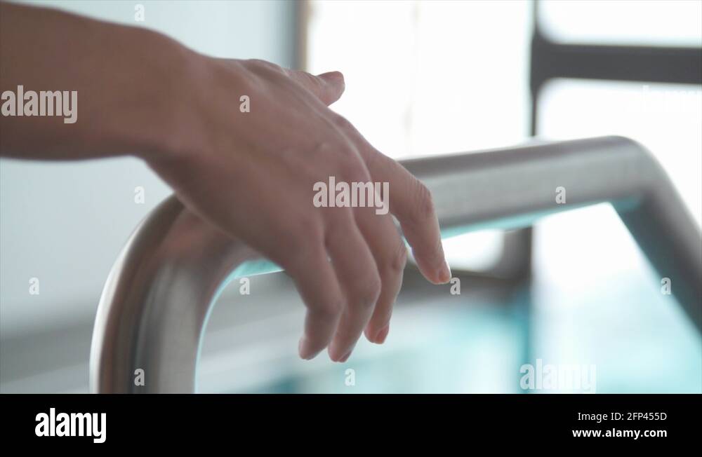 Close-up of a woman hand stepping into a pool at a luxury spa resort ...