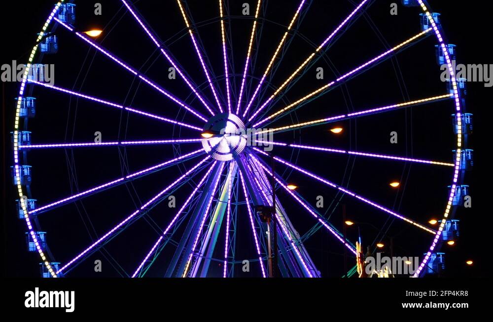 Giant ferries wheel at amusement park in motion with colorful ...