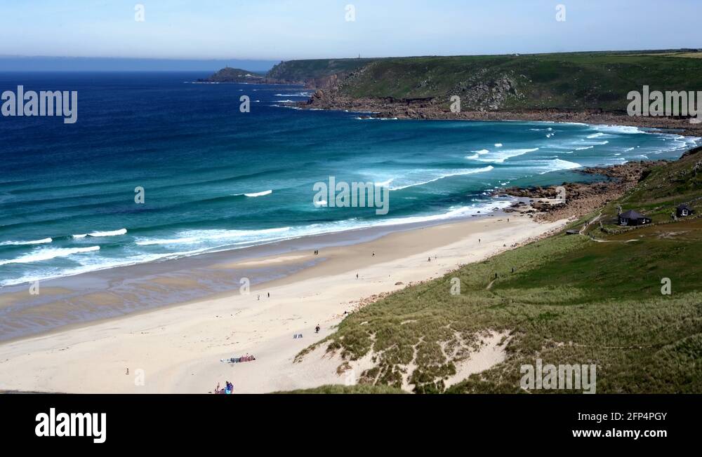 Ocean waves along the wide sandy shore at Sennen Cove in Cornwall with ...