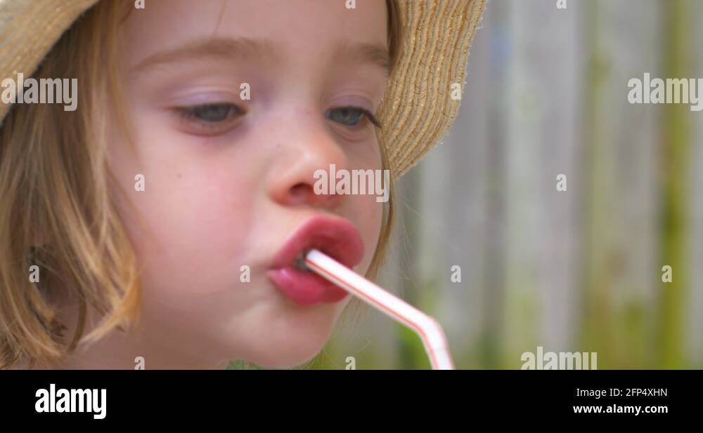 A happy little girl takes a sip of her drink and then smiles at the ...