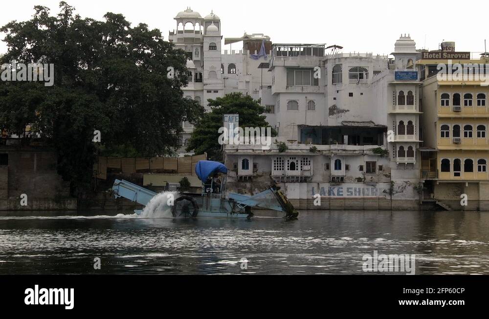 A trash collection boat skims the water surface for floating garbage in ...